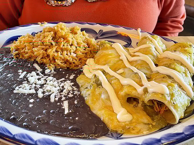 These enchiladas verdes aren't just draped in sauce&mdash;they're wearing a silky green robe with a crema crown. Rice and beans play perfect supporting roles.