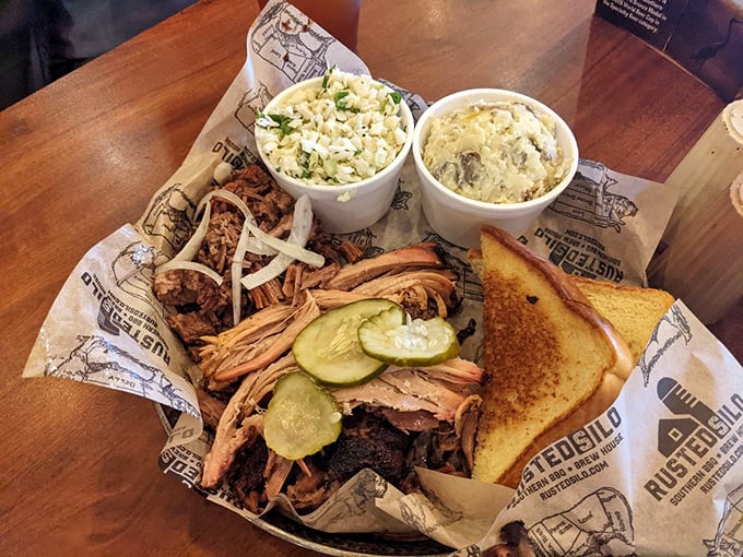 Barbecue artistry on display: pulled pork nestled beside creamy mac and cheese, with pickle coins providing that perfect acidic counterpoint. Texas toast completes this masterpiece.