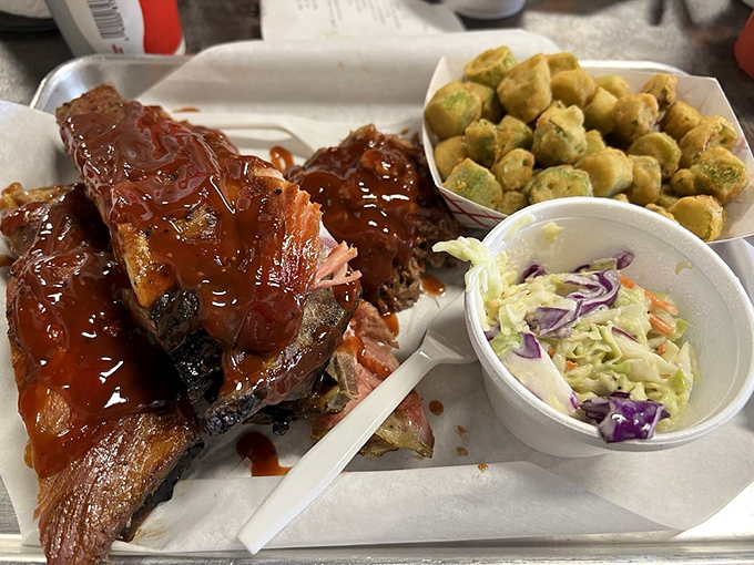 Glistening ribs basking in sauce alongside golden-fried okra and creamy slaw. This plate isn't just lunch&mdash;it's what food dreams are constructed from.