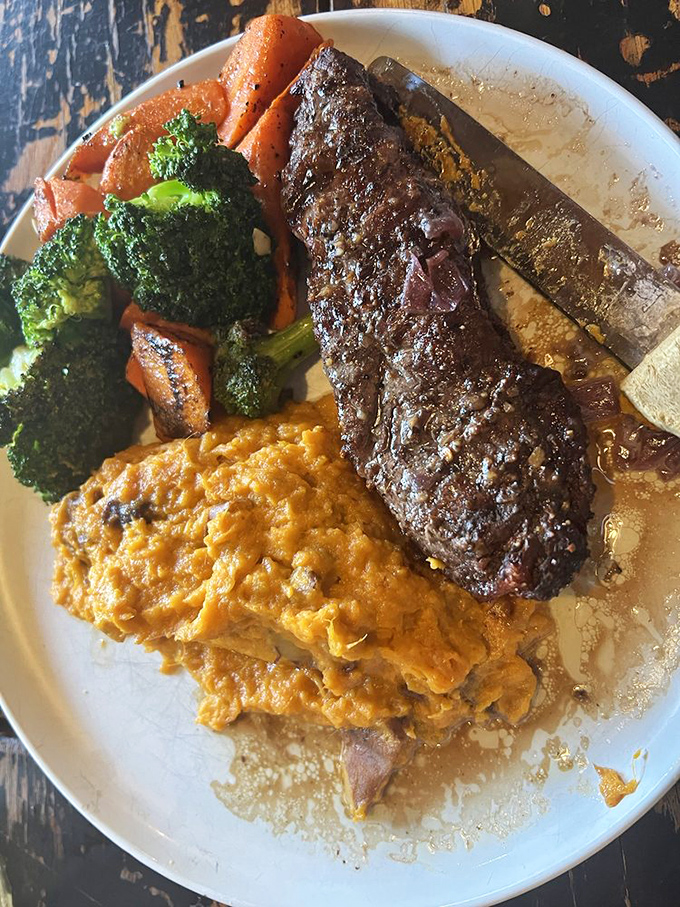 A perfectly seared strip steak shares the plate with vibrant vegetables and cheesy potatoes &ndash; the holy trinity of steakhouse perfection.