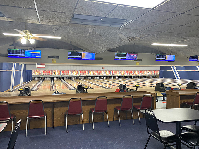League night scoreboard screens illuminate the alley with digital precision, while the classic wood seating areas maintain that perfect retro bowling ambiance.