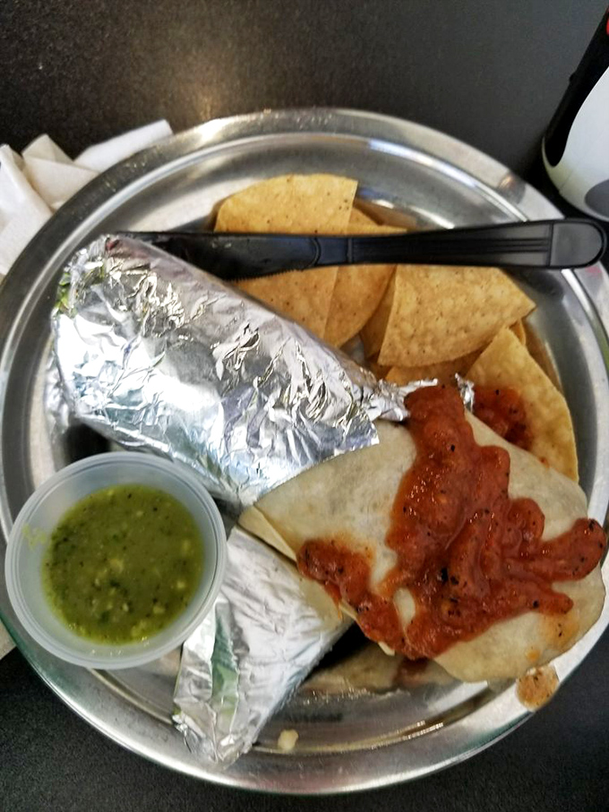 Behold the holy trinity of Mexican street food: a foil-wrapped burrito, fresh tortilla chips, and that magical green salsa that haunts your dreams.