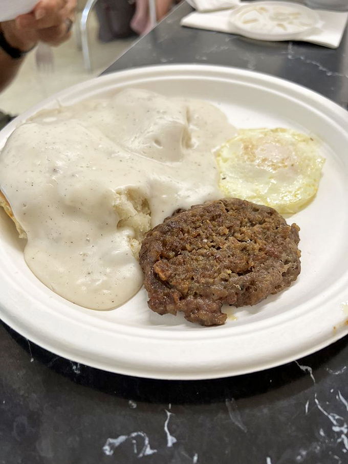 Country sausage patty lounging in a pool of creamy pepper gravy - proof that simple food done right is culinary poetry.