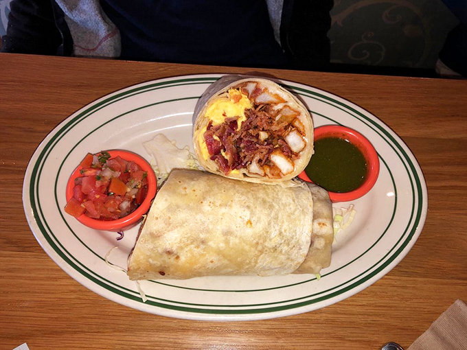 Behold, the breakfast burrito in its natural habitat! Two salsas standing guard like loyal sentinels protecting a treasure of eggs, meat, and morning bliss.