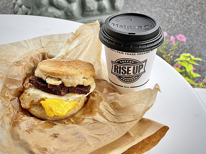 Breakfast nirvana on brown paper: a golden-yolked masterpiece nestled in a scratch-made biscuit, paired with coffee that makes mornings bearable again.