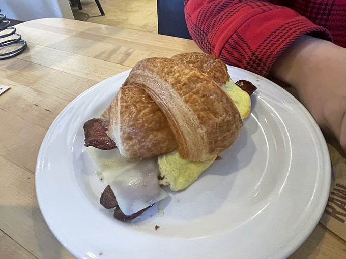 Breakfast architecture at its finest&mdash;a golden croissant cradles perfectly scrambled eggs, bacon, and melted cheese in delicious harmony.