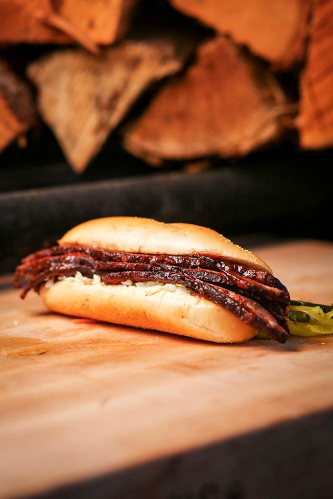 This isn't just a sandwich; it's a monument to patience. Tender strands of brisket nestled in a pillowy bun&mdash;proof that simplicity often tastes best.