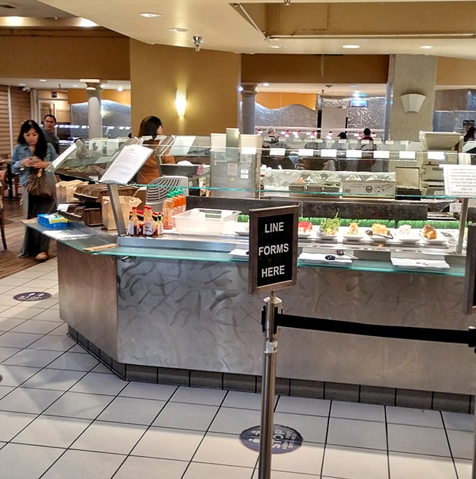 The buffet ordering station &ndash; where food dreams begin and diet plans go to die. That "Line Forms Here" sign might as well say "Patience Rewards."