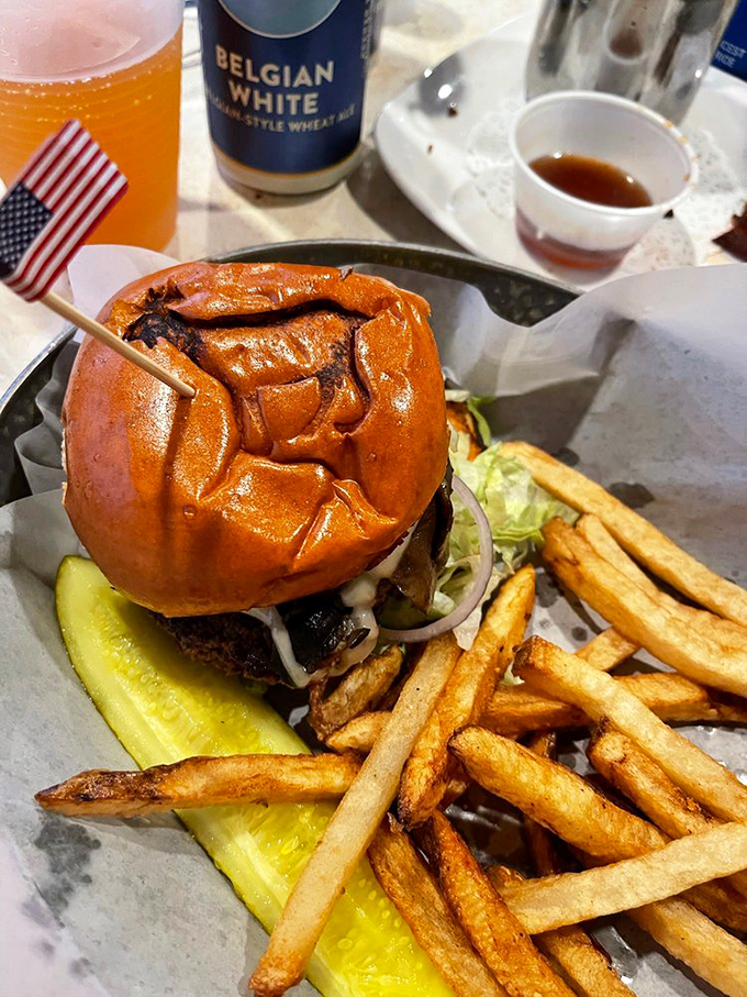 This isn't just a burger&mdash;it's an architectural marvel with a pickle foundation and golden fry buttresses. The American flag toothpick claims this territory for deliciousness.