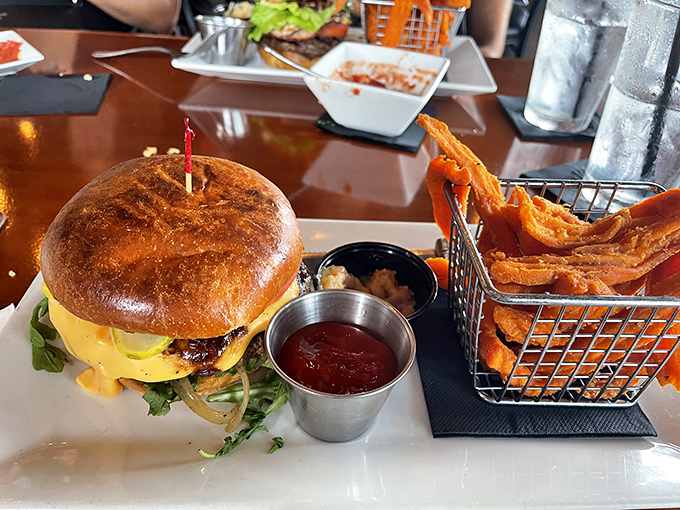 A burger so photogenic it deserves its own Instagram account, complete with sweet potato fries that could make a carb-counter reconsider life choices.