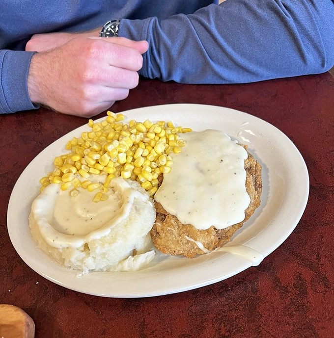 Behold the star of our show: chicken fried steak swimming in creamy gravy alongside mashed potatoes and corn. Diets come here to die gloriously.