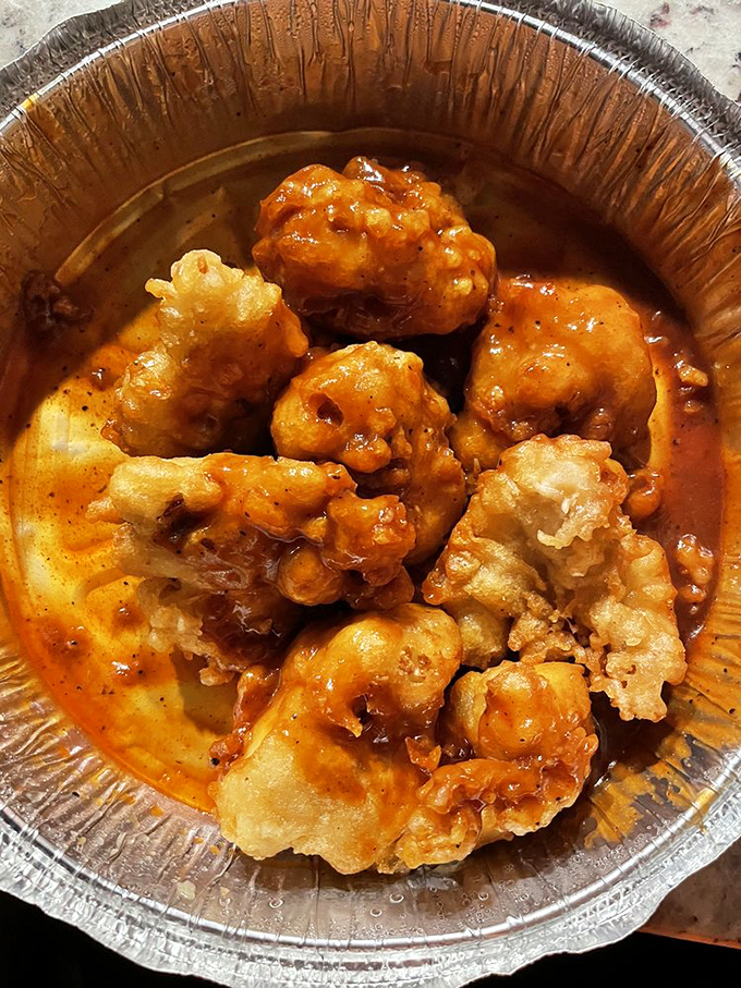 These golden-fried cauliflower bites swim in hot sauce like tiny asteroids in a deliciously spicy nebula.