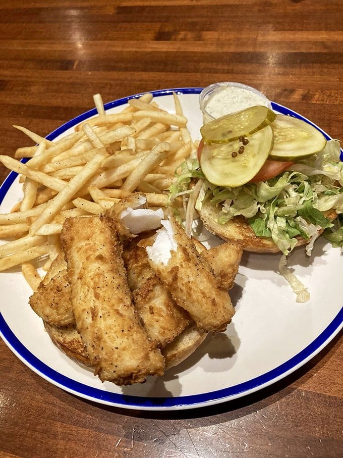 The fried cod sandwich arrives like crispy golden armor protecting tender fish treasure. Those fries could make a potato weep with pride.