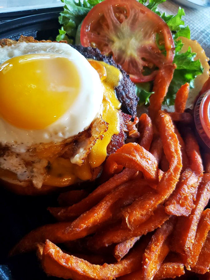 The signature Kuma burger arrives like a beautiful disaster&mdash;melted cheese cascading over bacon with a sunny-side-up egg standing sentry. Sweet potato fries complete the symphony.