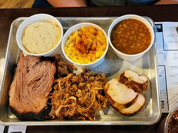 BBQ perfection on a metal tray: brisket, pulled pork, chicken, mac and cheese, and beans. This isn't a meal; it's a celebration of smoke and patience.