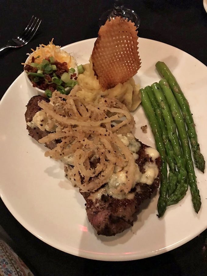 This isn't just steak&mdash;it's a masterpiece with crispy onion strings and perfect sides. The kind of plate that makes conversation stop mid-sentence.
