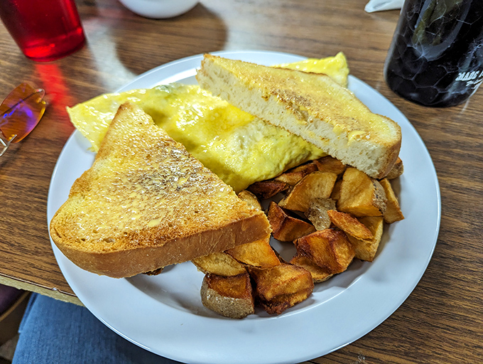Behold the perfect omelet trifecta: golden eggs, perfectly toasted bread, and home fries that could make a potato farmer weep with joy.