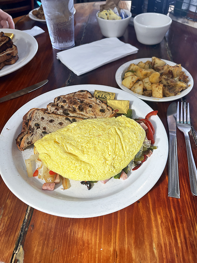 This isn't just an omelet&mdash;it's a golden-hued envelope stuffed with colorful treasures, served with raisin toast that makes ordinary bread seem like a missed opportunity.