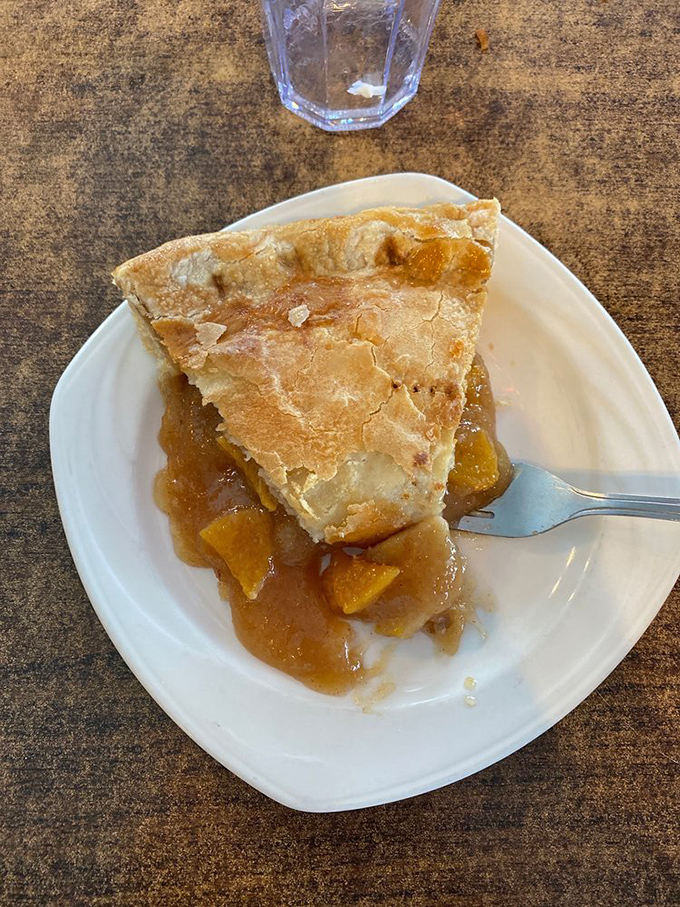 This isn't just peach pie; it's summer sunshine captured between two crusts. The fork stands ready for its noble purpose.