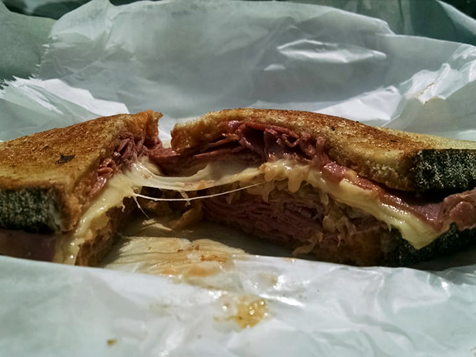 Behold the cross-section of perfection: layers of corned beef, sauerkraut, and melted Swiss create a Reuben that demands a moment of silent appreciation.