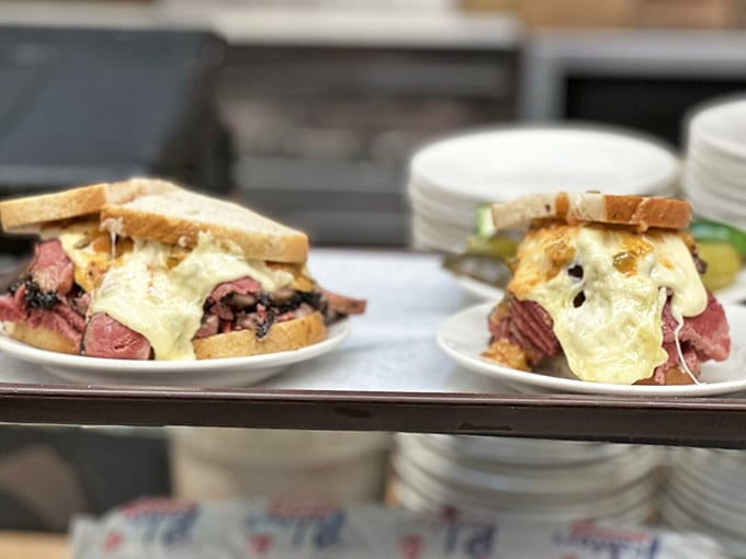 Behold, the Reuben in its natural habitat. Not so much a sandwich as a monument to what happens when corned beef meets Swiss cheese and refuses to compromise.