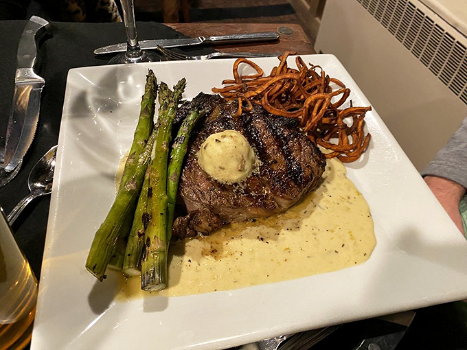 A steak that demands silence when it arrives. The compound butter slowly melting atop this masterpiece is performing the culinary equivalent of a victory lap.