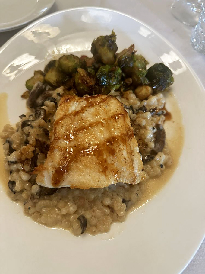 Sea bass perched atop creamy risotto like it was born to be there, with roasted Brussels sprouts standing guard. A plate that makes you pause mid-conversation.