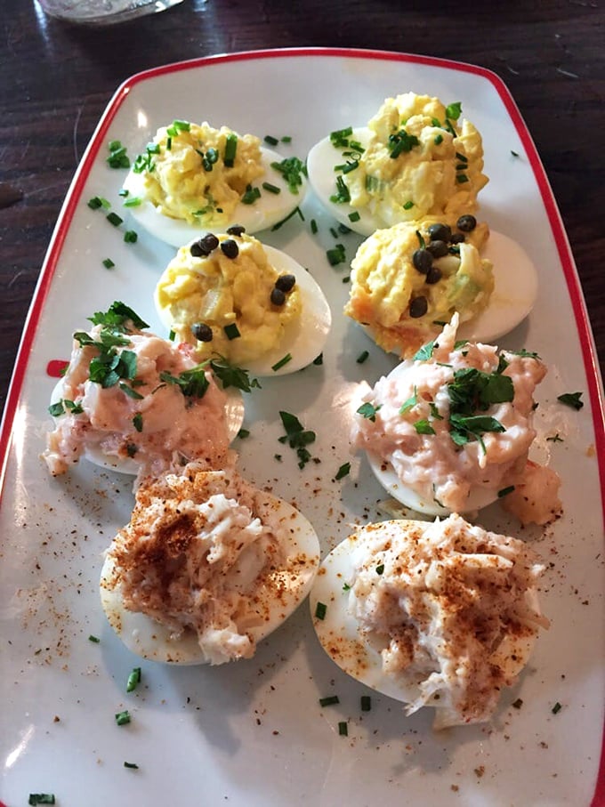 Deviled eggs elevated to an art form! Three distinct varieties showcase the kitchen's creativity&mdash;classic paprika, fresh herbs, and what appears to be capers adding playful pops of flavor.