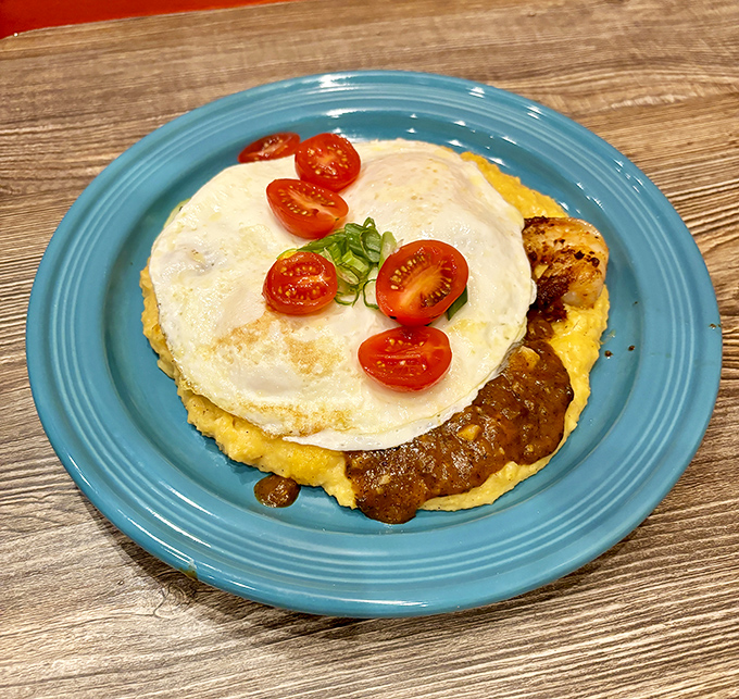 A sunny-side-up egg crowns this polenta kingdom like breakfast royalty, with cherry tomatoes serving as the court jesters of this plated monarchy.