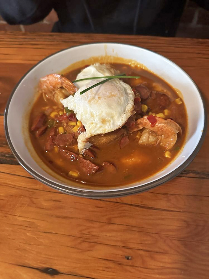 Shrimp swimming in a savory broth topped with a perfectly poached egg&mdash;proof that breakfast can be both sophisticated and soul-satisfying.