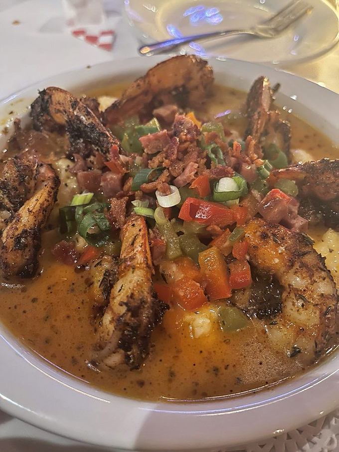 These blackened shrimp perch atop creamy grits like royalty on a throne, surrounded by a court of colorful vegetables and bacon.