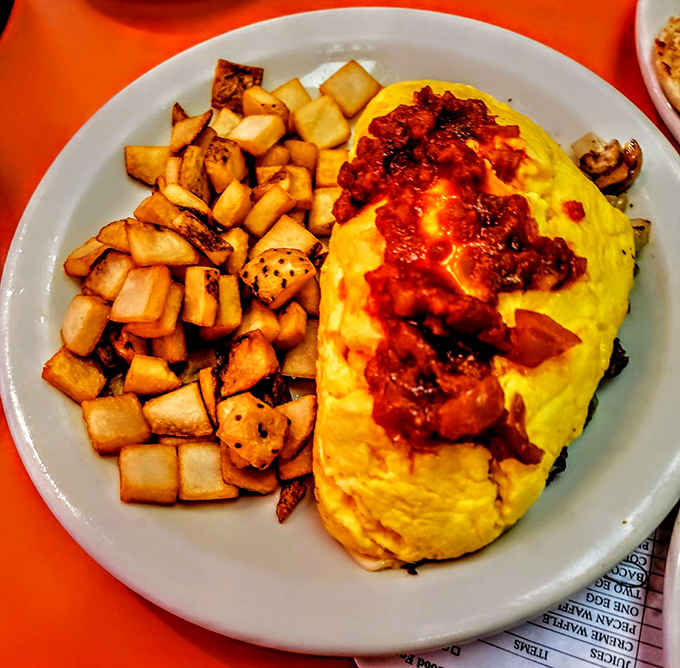 This isn't just an omelet &ndash; it's edible architecture with golden eggs embracing steak and cheese, perfectly complemented by crispy cubed home fries.