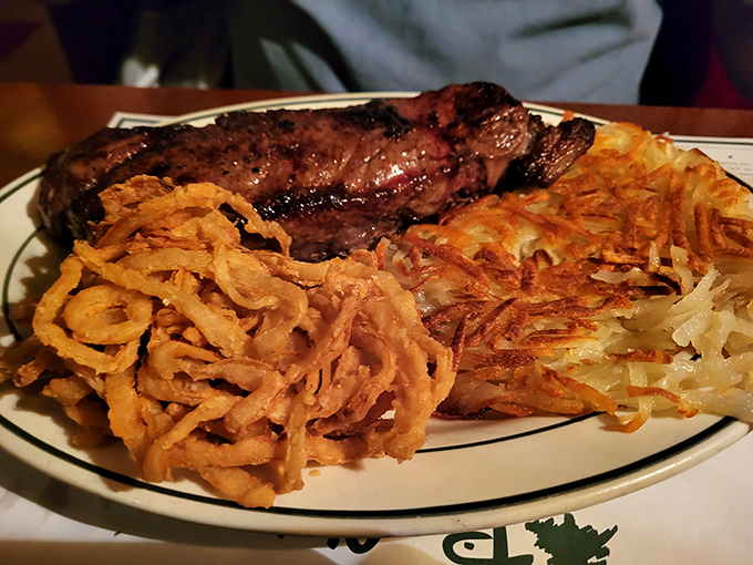 Carnivore's delight: A perfectly seared steak flanked by golden onion rings and hash browns &ndash; the holy trinity of steakhouse indulgence.