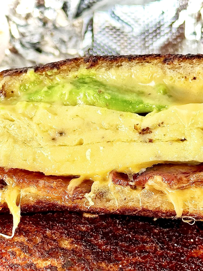 Cross-section of heaven: melted cheese embracing avocado while egg and bacon provide the harmony. It's the breakfast equivalent of a perfect Beatles song.