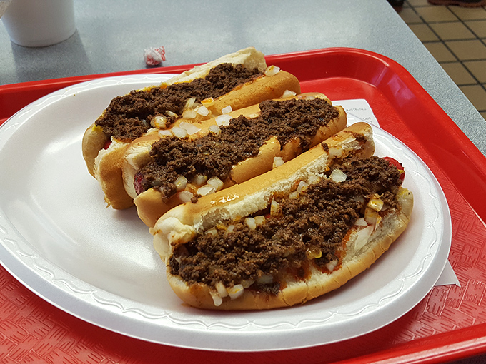 Three perfect chili dogs lined up like old friends at a reunion. That meaty chili blanket isn't just a topping&mdash;it's the reason people make pilgrimages here.