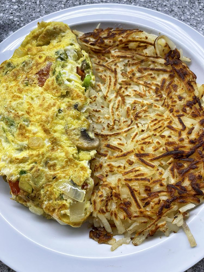 This veggie omelet doesn't just sit on the plate&mdash;it commands real estate, sharing borders with hash browns that deserve their own zip code.