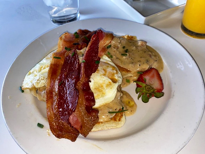 Breakfast architecture at its finest. Crispy bacon stands guard over eggs and biscuits swimming in gravy that could make a Southern grandmother weep with joy.