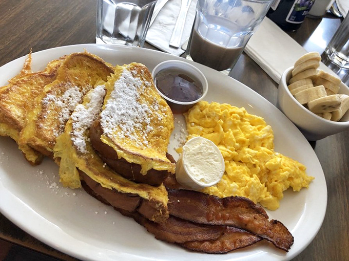 French toast that's dressed for success &ndash; powdered sugar formalwear, bacon accessories, and eggs that clearly graduated from free-range university.