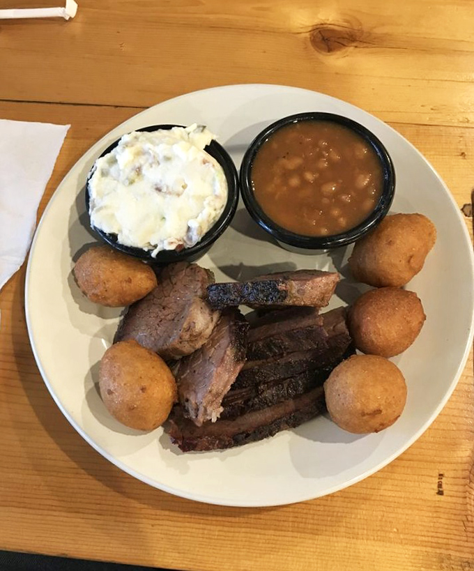 Barbecue nirvana on a plate: smoky brisket with that telltale pink ring, creamy potato salad, baked beans, and hushpuppies that deserve their own fan club.