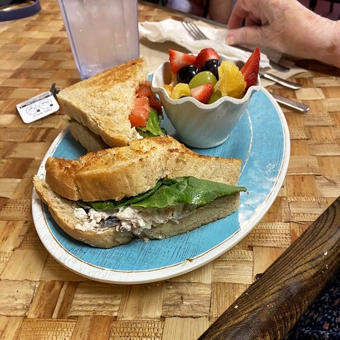 This chicken salad sandwich isn't trying to reinvent the wheel—it's just perfecting it with fresh bread, crisp greens, and a side of colorful fruit that makes lunch feel like a celebration.