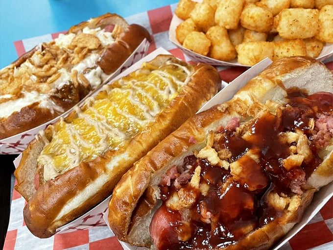 Hot dog heaven comes in threes: chili cascading over one, cheese blanketing another, and crispy tots standing by. The holy trinity of comfort food.