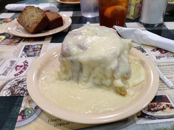 Behold the cinnamon roll in its natural habitat—swimming in a pool of icing that's making a break for freedom across the plate.
