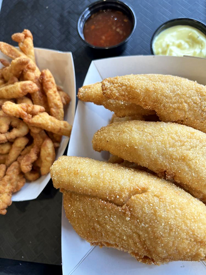 Golden-fried clam strips nestled beside crispy fries &ndash; a duo that belongs together like Bogart and Bacall. The accompanying sauces stand ready for their supporting roles.