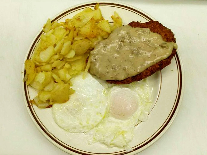 The holy trinity of breakfast perfection: golden home fries, sunny-side-up eggs, and that legendary country fried steak swimming in pepper-flecked gravy. Morning salvation on a plate.
