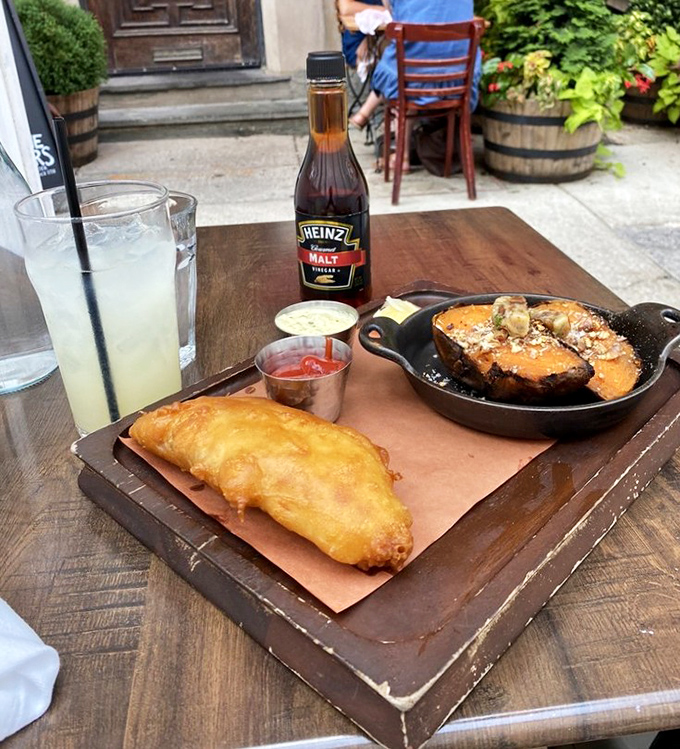 Fish and chips perfection doesn't happen by accident. This golden-battered cod with triple-cooked chips and that essential malt vinegar bottle standing guard is British diplomacy on a plate.