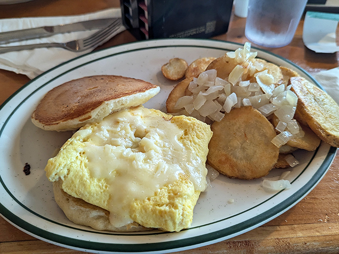 Breakfast architecture at its finest&mdash;a golden-yellow omelet nestled beside home fries that glisten with oniony promise. Simple perfection on a plate.