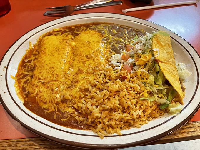 This isn't just dinner; it's edible artwork. Golden enchiladas swimming in sauce, perfectly seasoned rice, and a crispy taco standing at attention like a delicious honor guard.