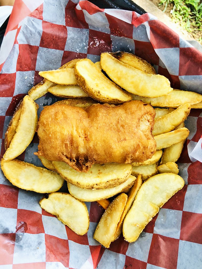 Golden-battered fish nestled among potato wedges like a sunbather on a beach of carbs &ndash; this is vacation on a red-checkered plate.