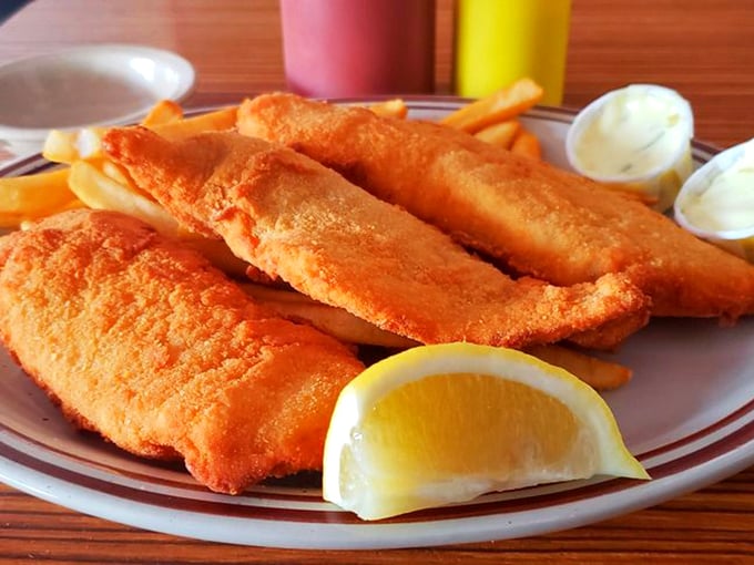 Golden-battered fish fillets that shatter with each bite, revealing flaky white perfection within. The lemon wedge isn't just garnish&mdash;it's essential equipment.