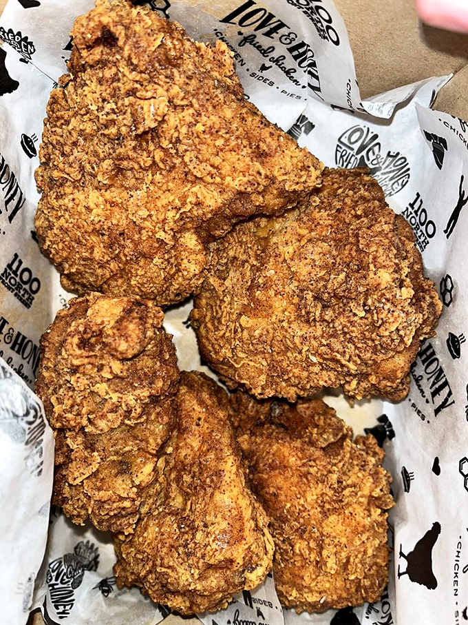 Golden-brown perfection nestled in branded paper—this isn't just fried chicken, it's edible artwork with a PhD in crunchology.